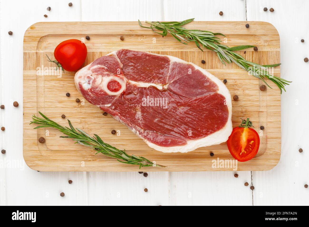 Raw lamb steak on board on white wooden table Stock Photo - Alamy