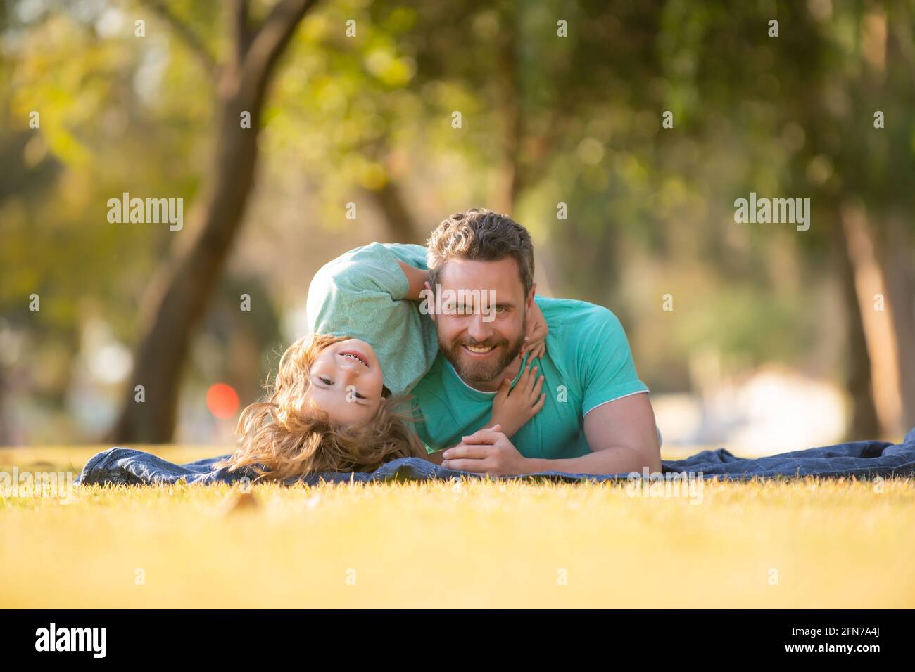 Father and son laying on grass in nature park. People having fun ...