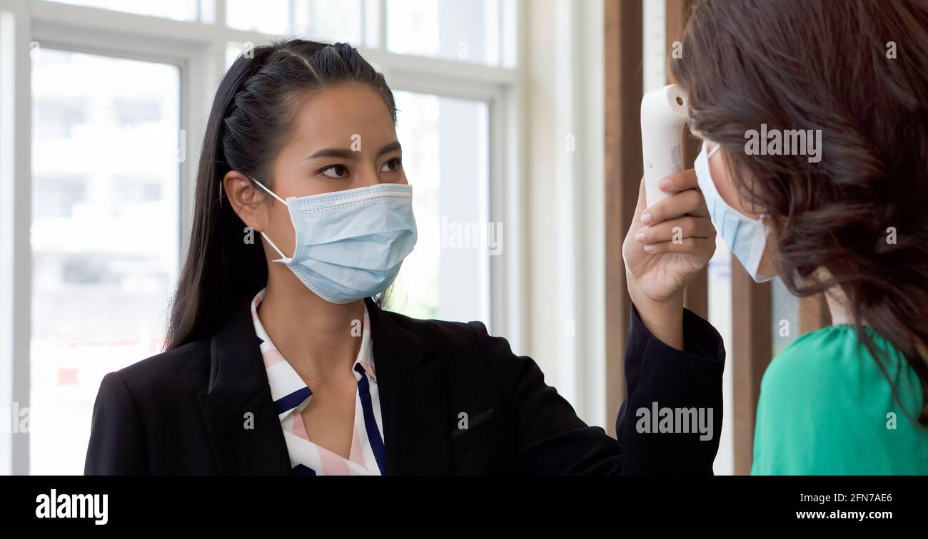 Hotel staff in black suit measuring tourist temperature with a fever ...
