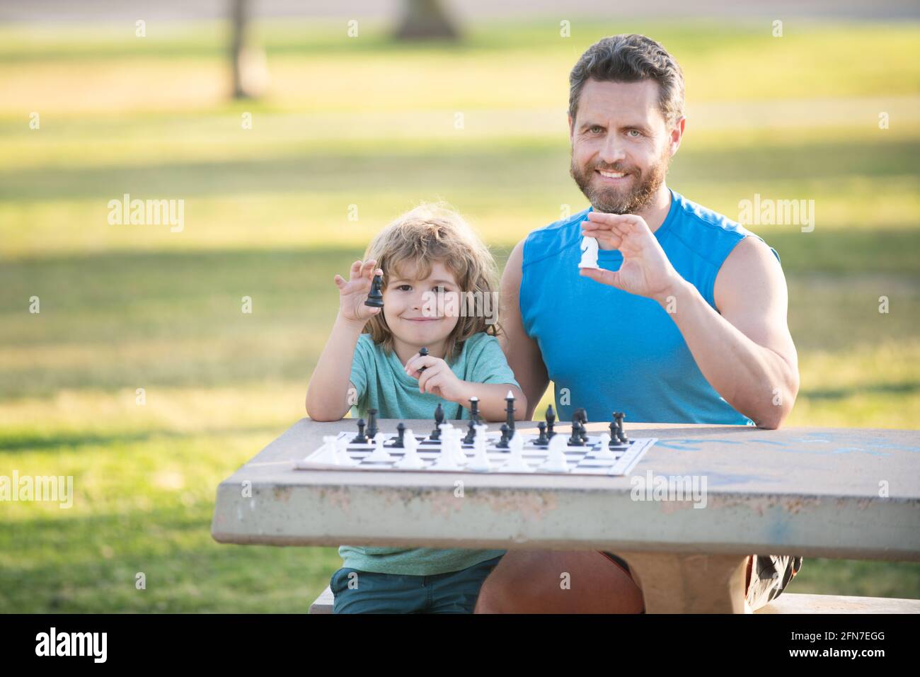Father and son playing chess spending time together in park. Kid play ...