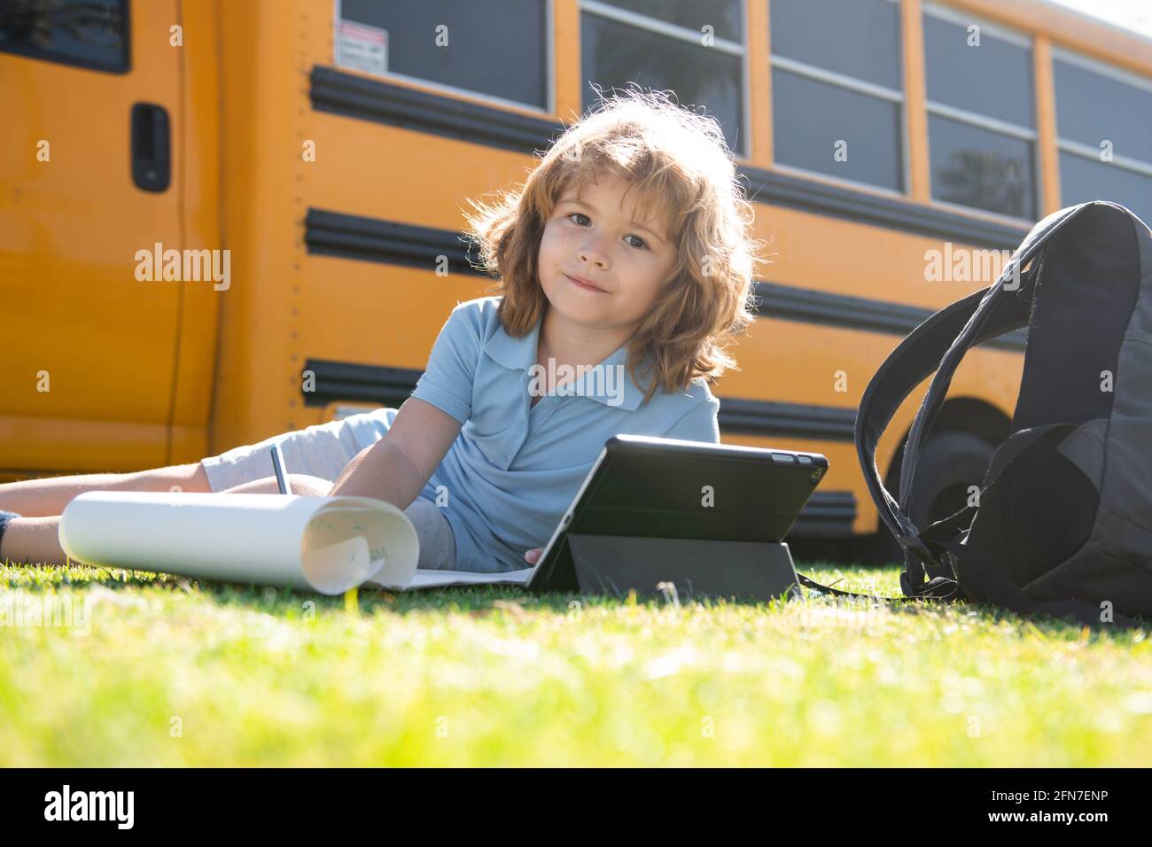 Smart school boy doing homework with digital tablet at school park near ...