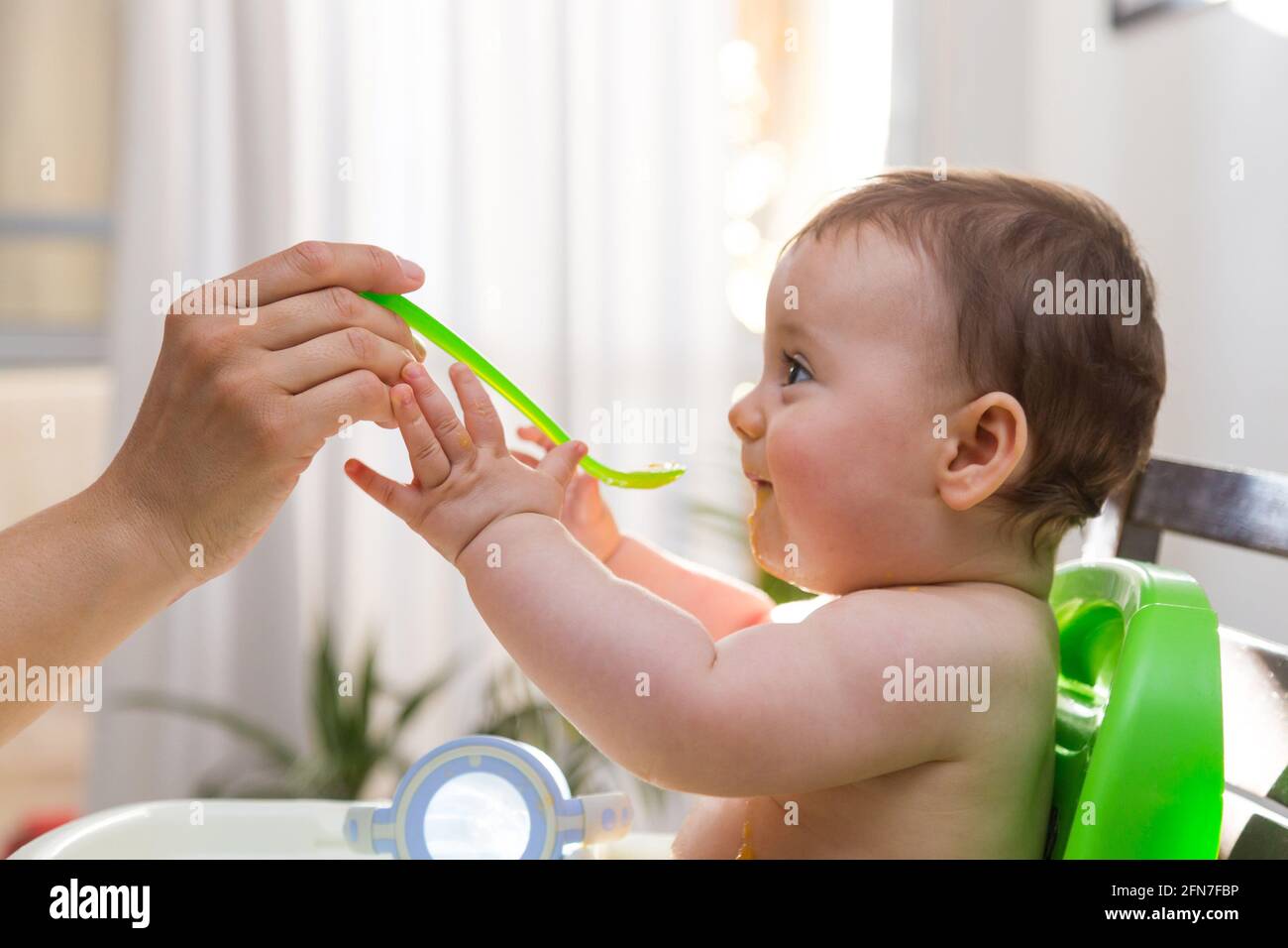 Adorable baby eating food. His mother feeds him with a spoon Stock ...