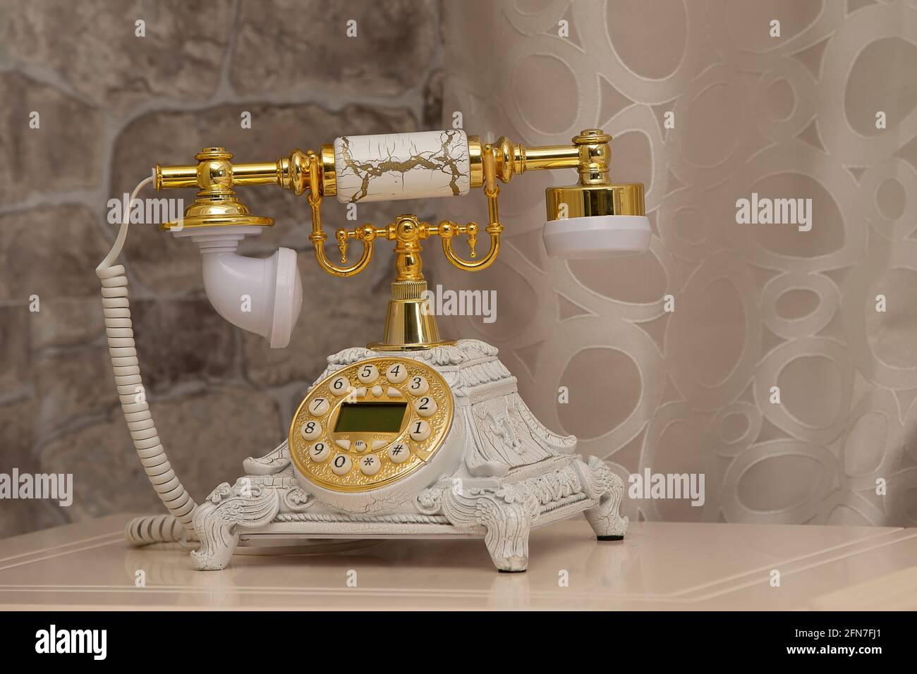 White retro telephone with a gold receiver on a wall background. The ...