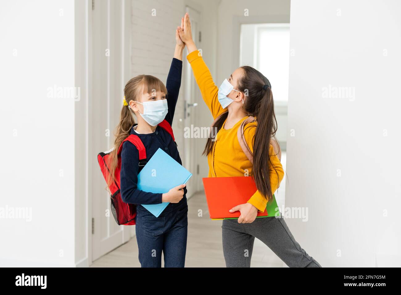 Cute little girls of primary hug each other with the mask on. School ...