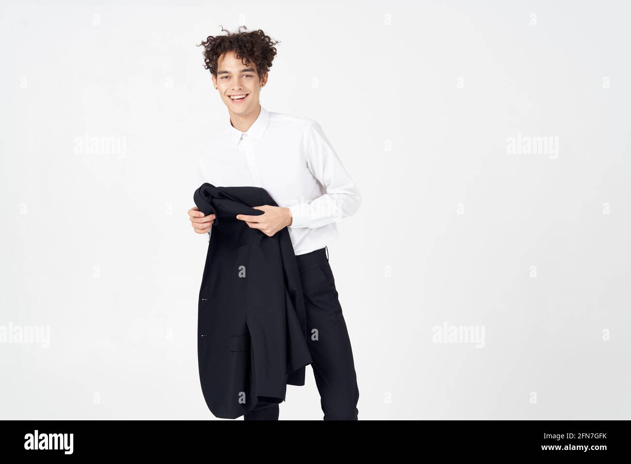 fashionable guy in a classic suit with a jacket in his hand on a light ...