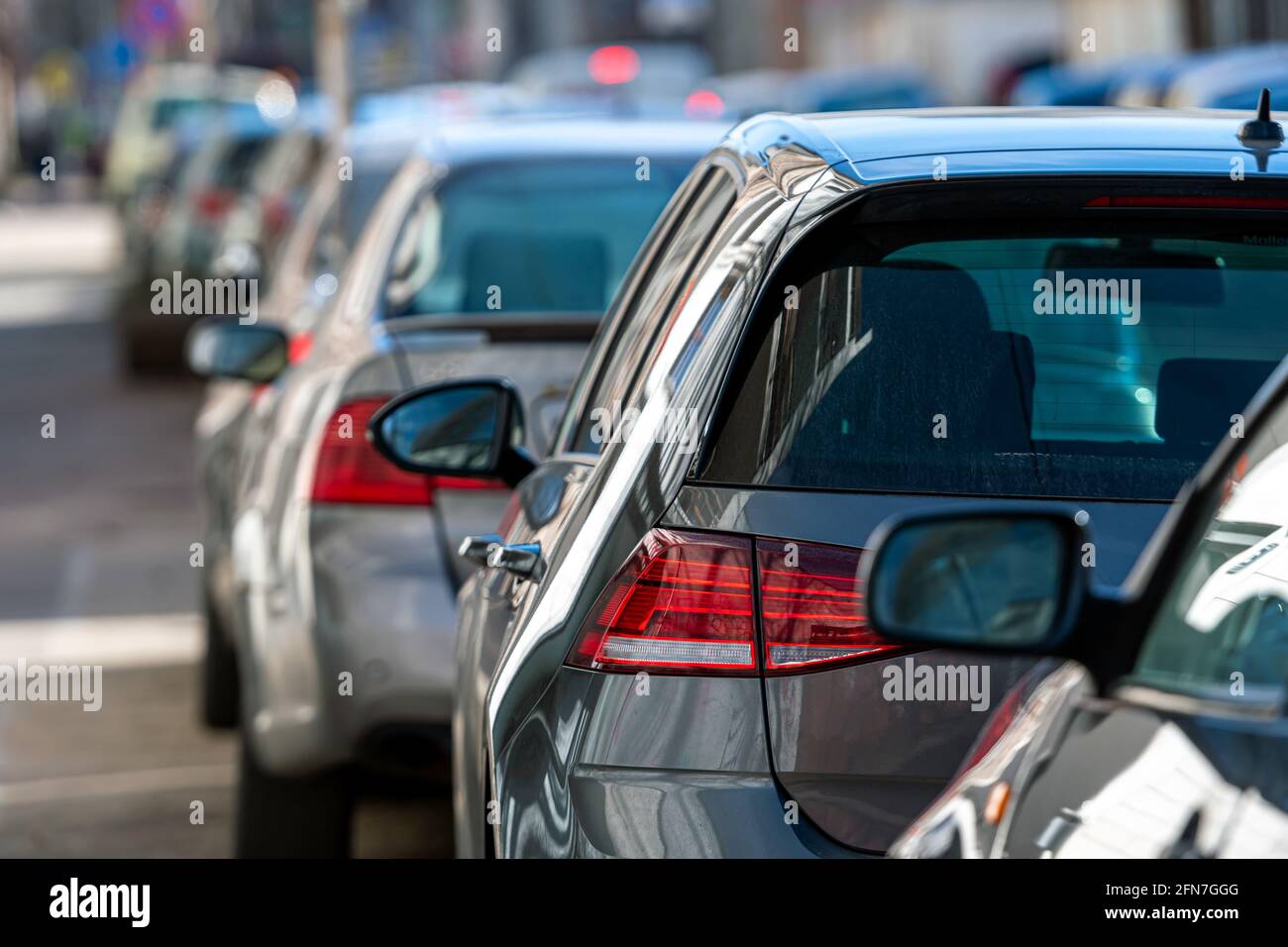 rows of different cars parked along the roadside in crowded city, close ...