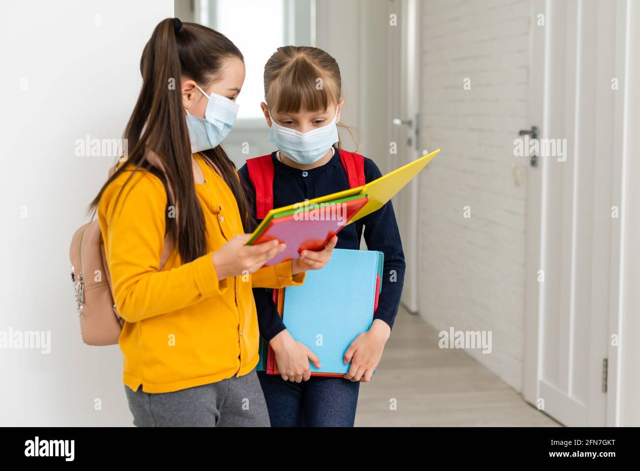 Cute little girls of primary hug each other with the mask on. School ...