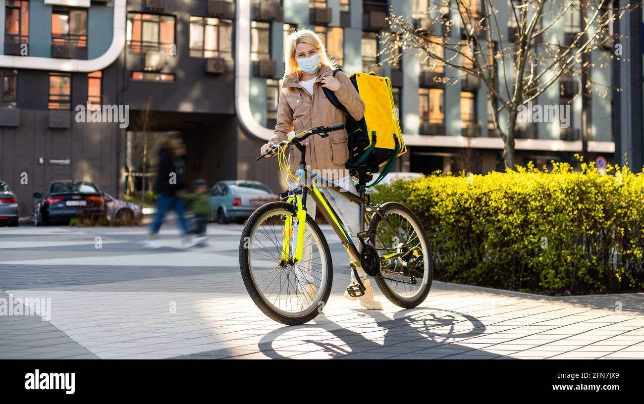Portrait of beautiful woman delivery worker in medical mask for riding ...