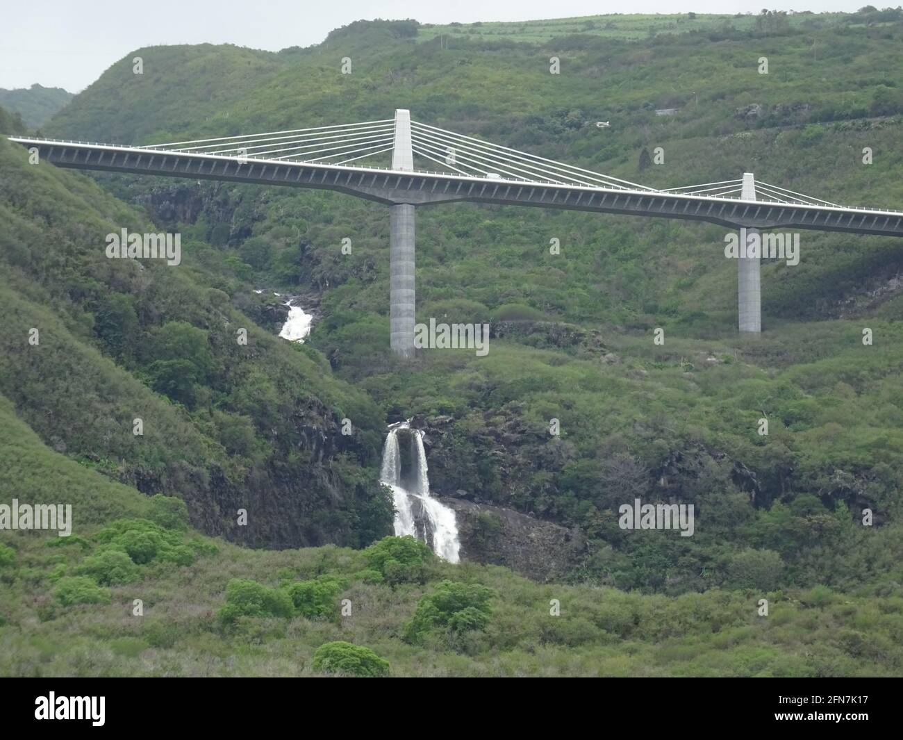 new stone bridge with cables above the river, waterfalls and mountains ...