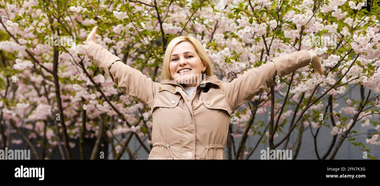 Beautiful woman enjoying sunny spring day in park during cherry blossom ...