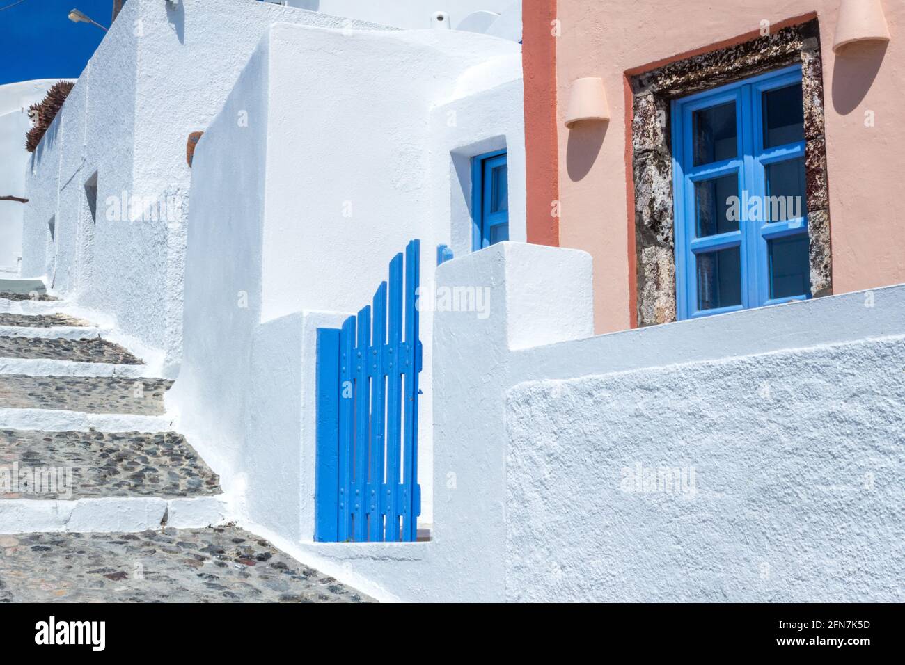A traditional, cobble stone street in Santorini with whitewashed walls ...