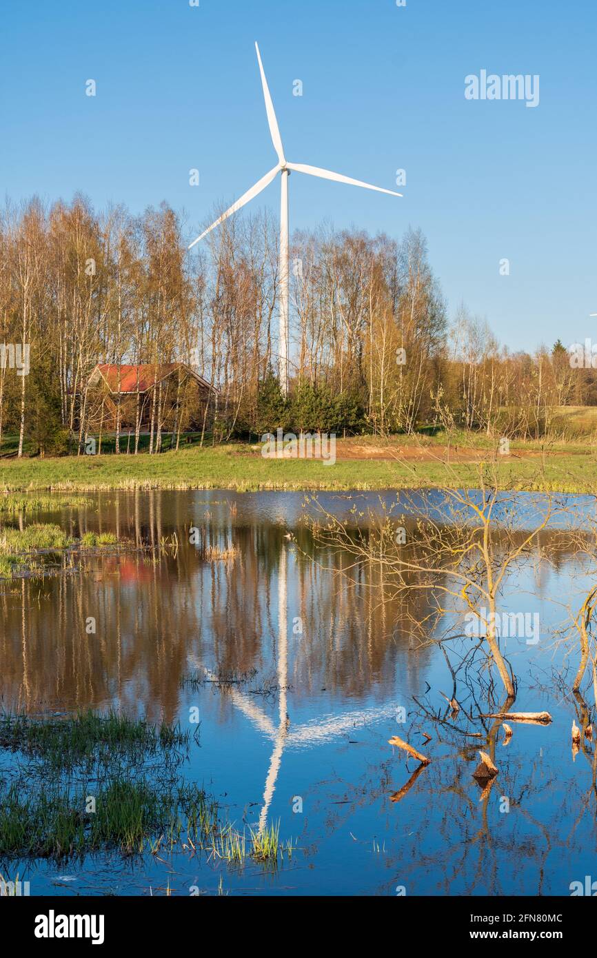 Wind turbine near a forest and lake with clear blue sky on background ...