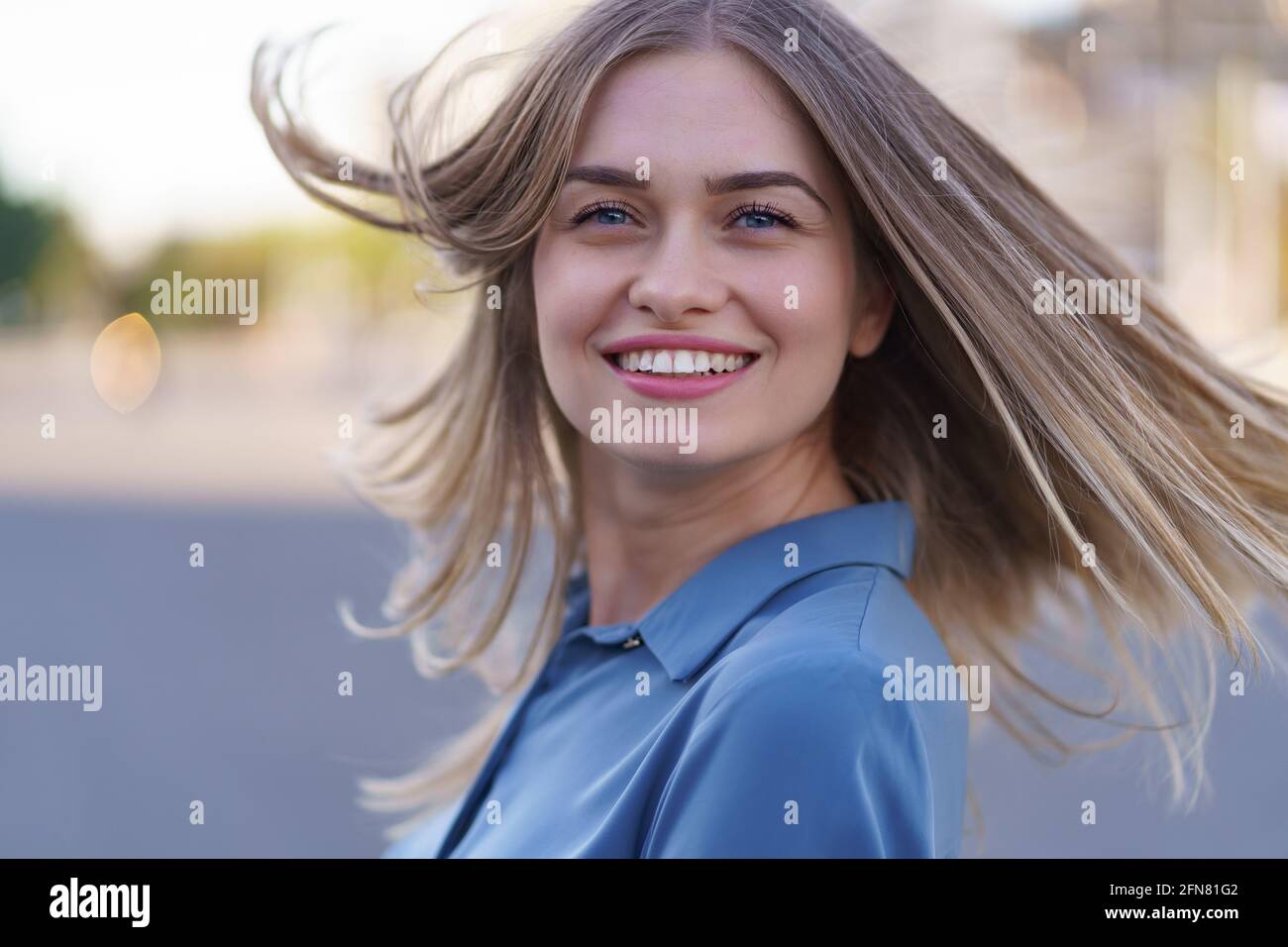 Attractive cheerful blonde girl with flying long hair smiling laughing ...