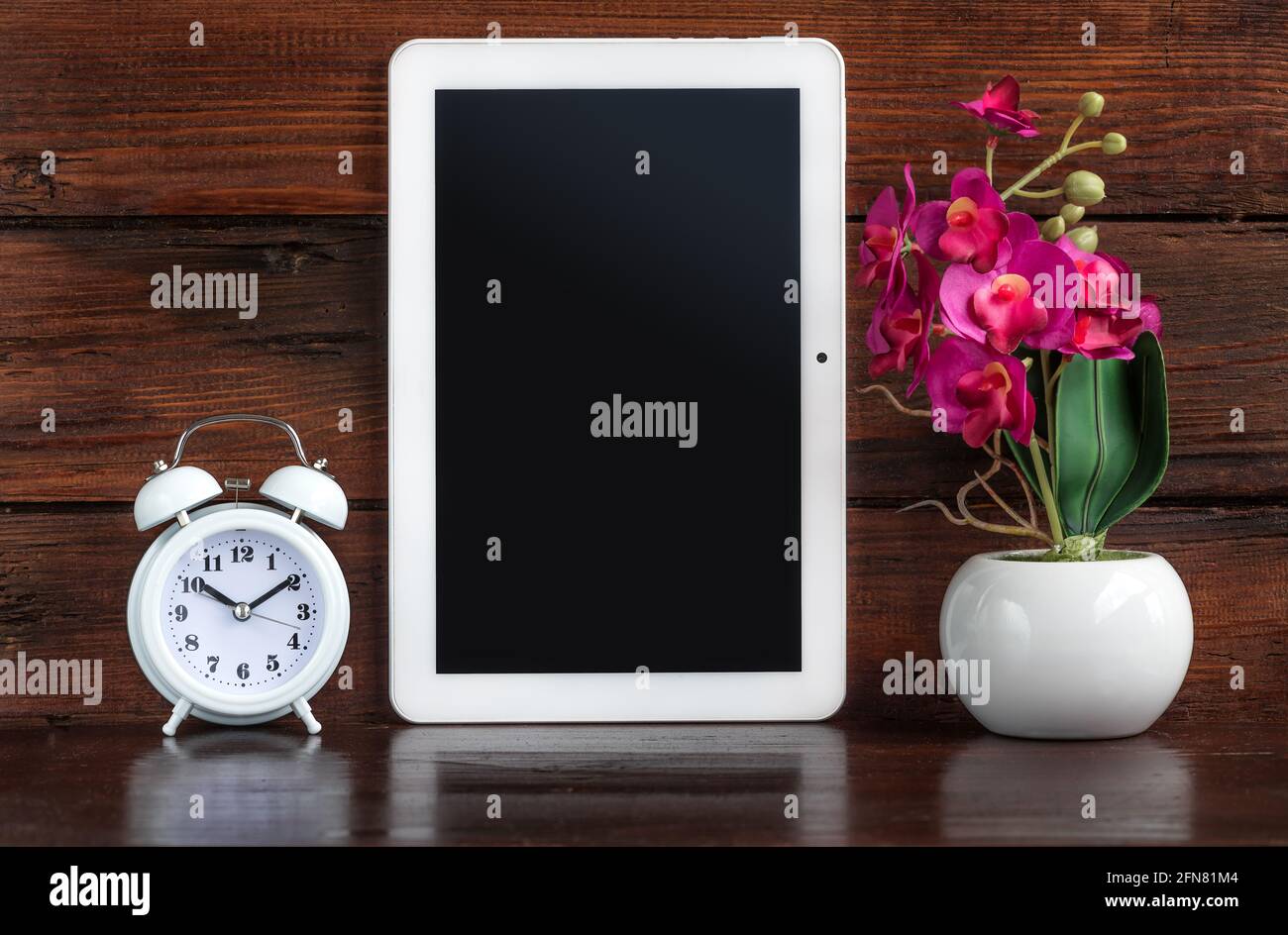 Tablet with Alarm clock and artificial flower decoration on a dark ...
