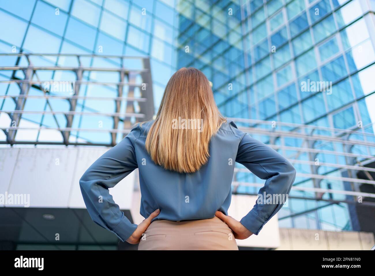 Back view of successful manager looking at business building of modern ...