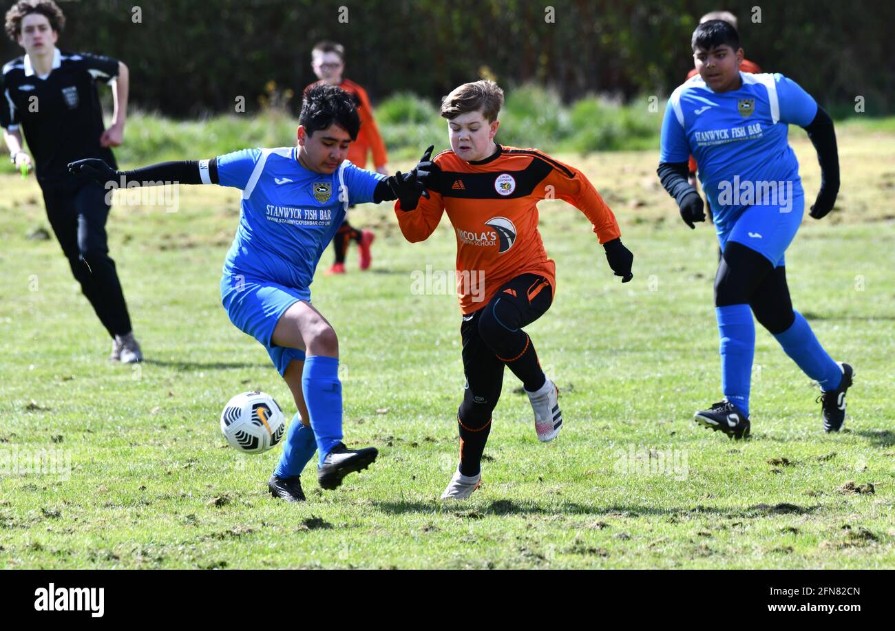 Boys junior football match action on uneven pitch Britain Uk Stock ...