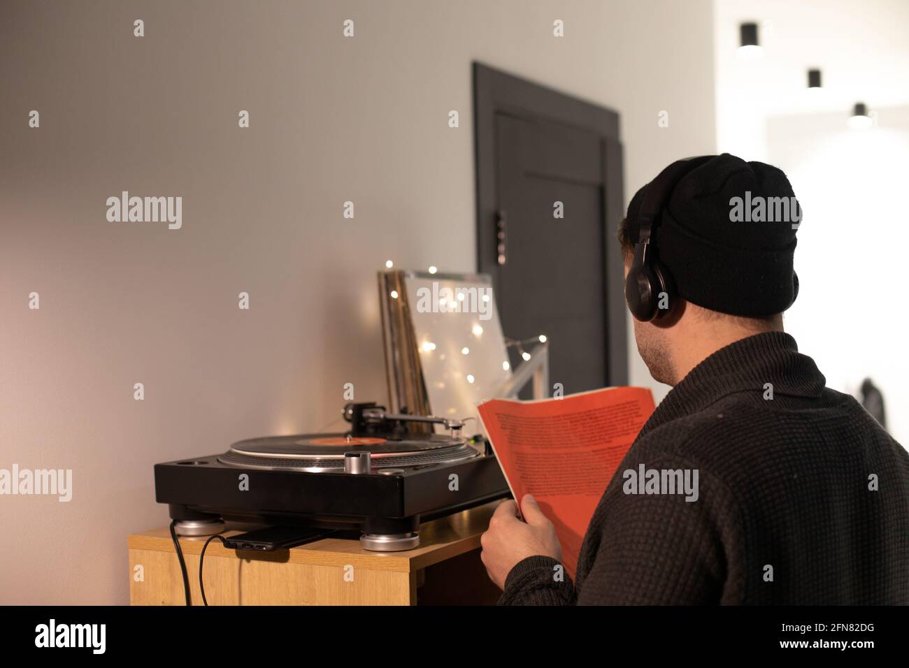 Young unshaven handsome hipster guy puts record on turntable from red ...