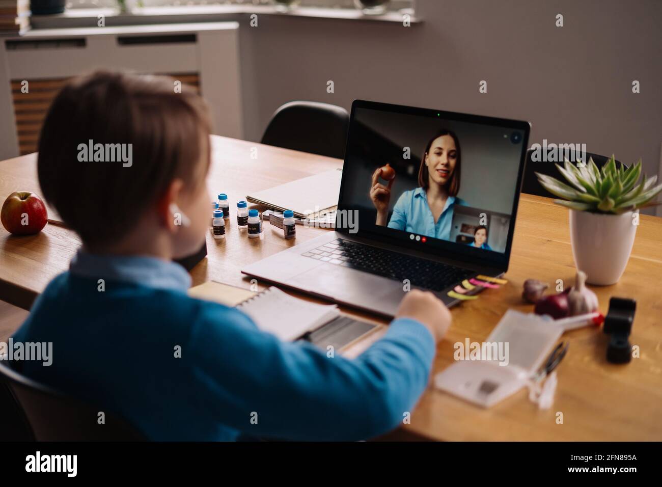 A Preteen boy uses a laptop to make a video call with his teacher. The ...