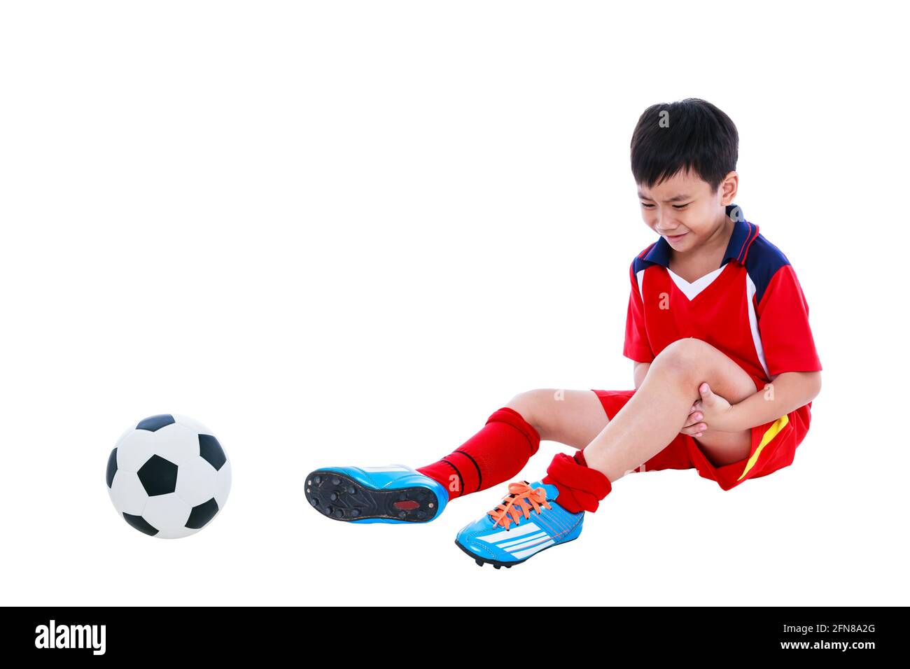 Sports injure. Youth asian soccer player with football in red uniform ...