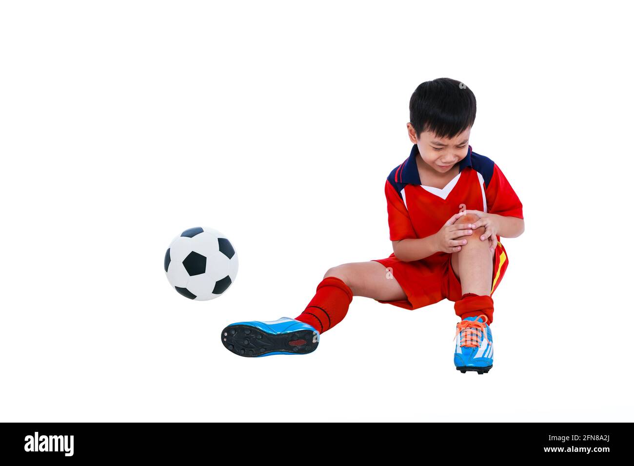 Sports injure. Youth asian soccer player with football in red uniform ...