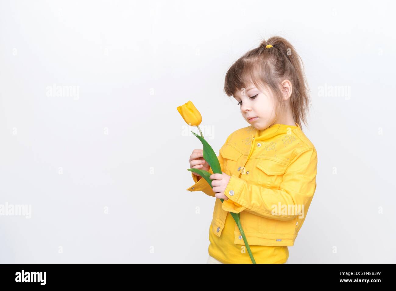 sad child girl in yellow clothes with yellow flowers Stock Photo - Alamy