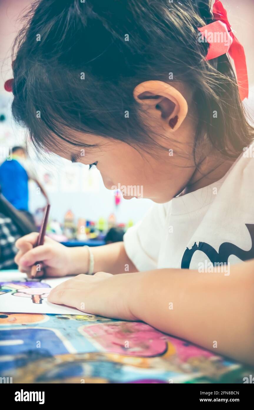 Happy asian girl drawing and painting on artwork with colored pencil ...