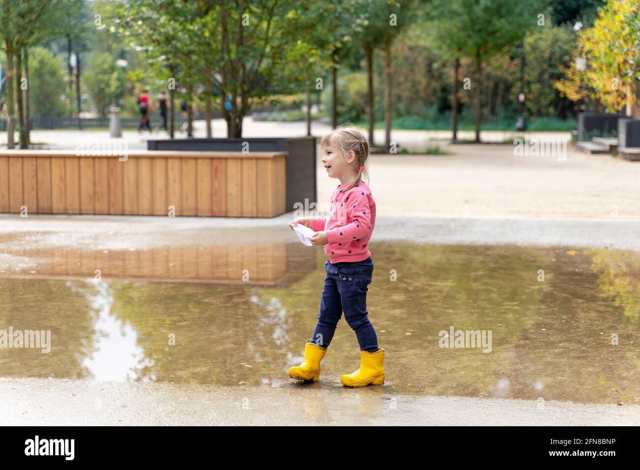 little girl playing with paper boats in puddle Stock Photo - Alamy