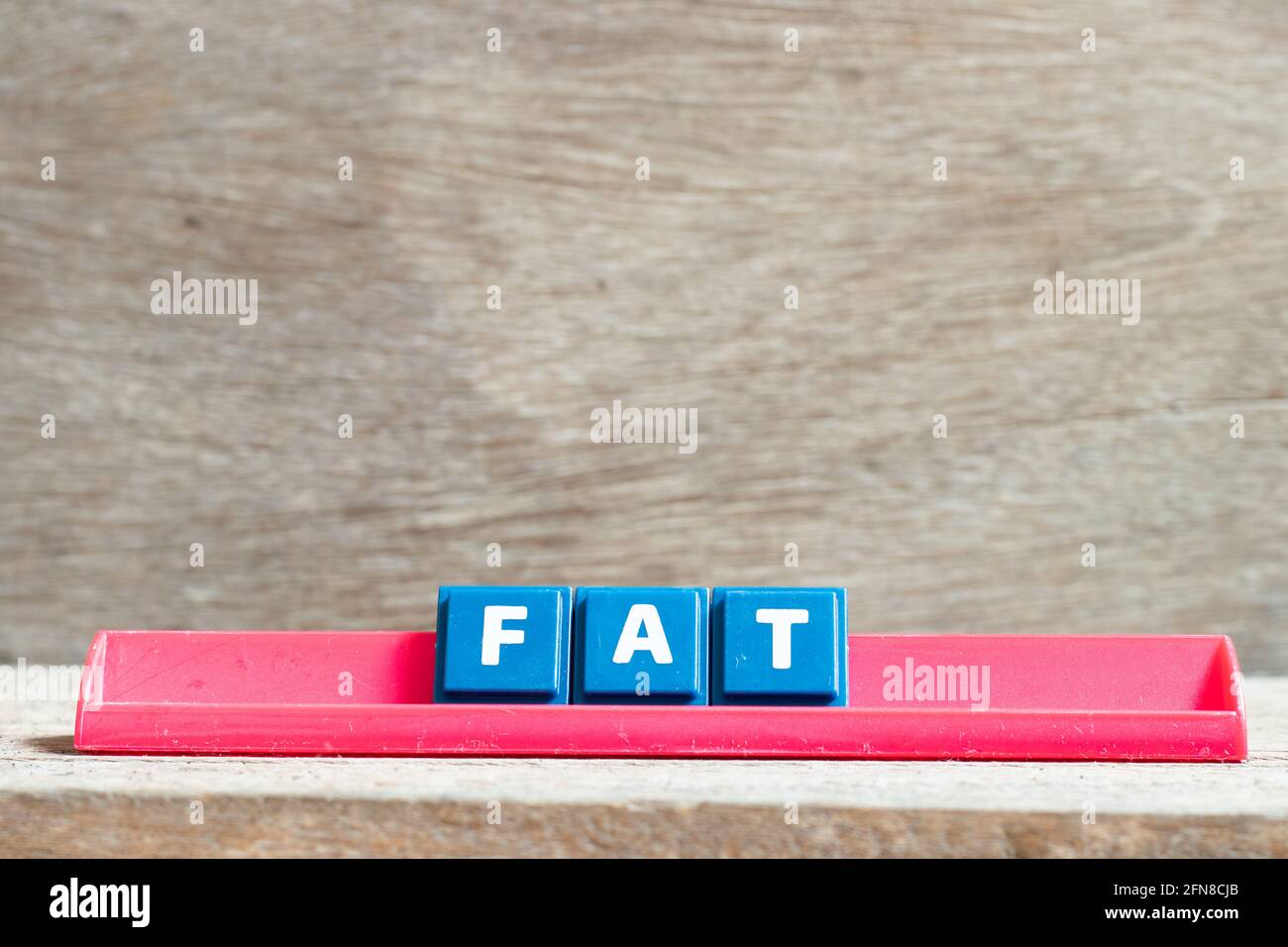 Tile letter on red rack in word FAT (Obesity or abbreviation of factory ...