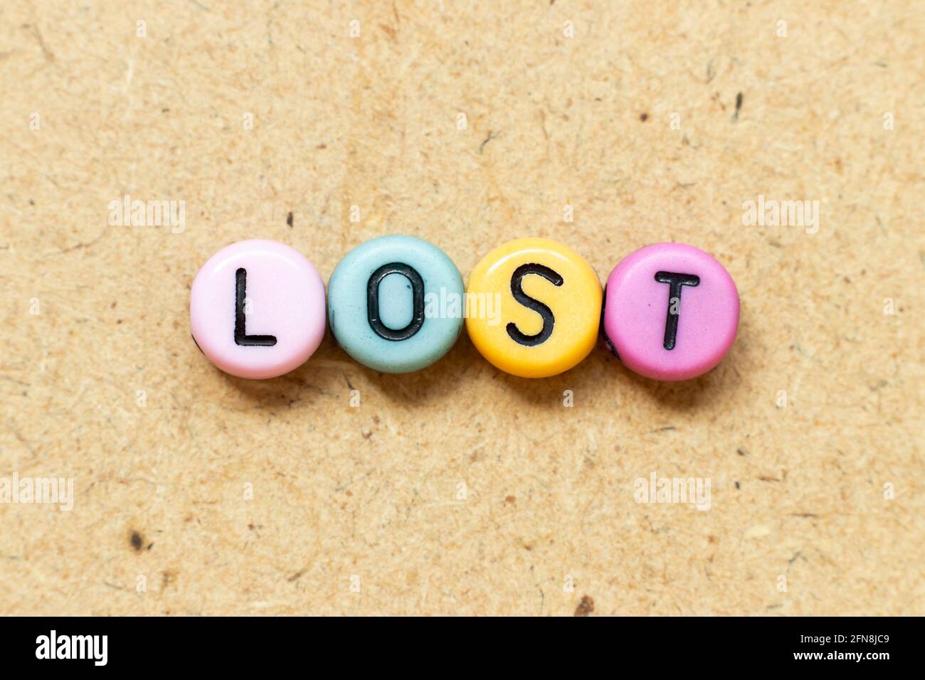 Round color bead with black letter in word lost on wood background ...