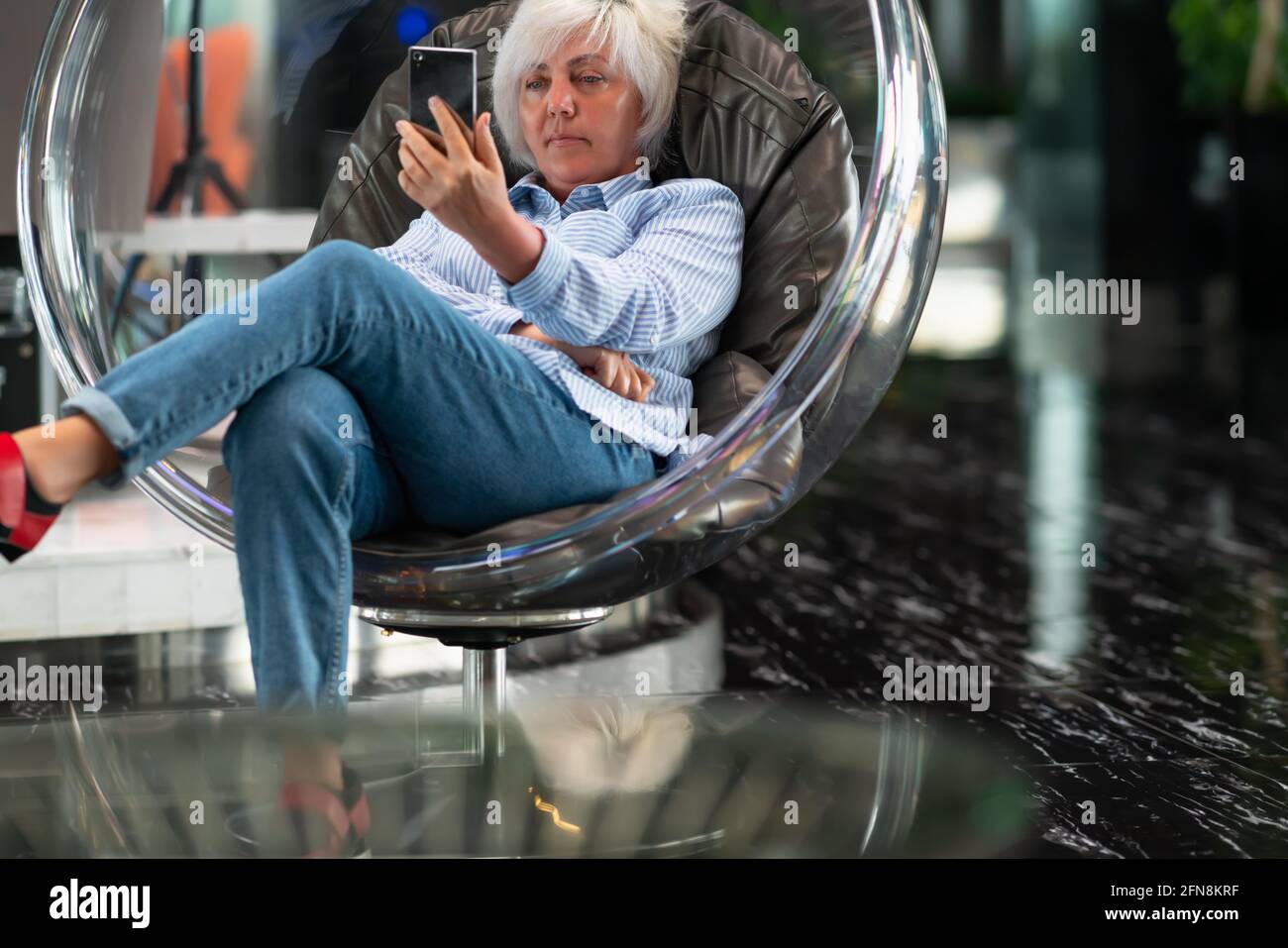 Woman engrossed in watching media on her smartphone relaxing in a ...