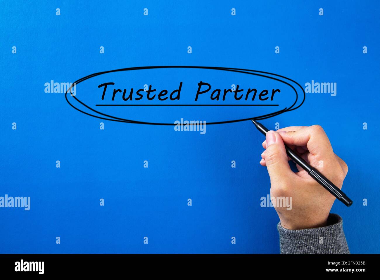 Businessman hand writing a Trusted partner sign with black marker over ...