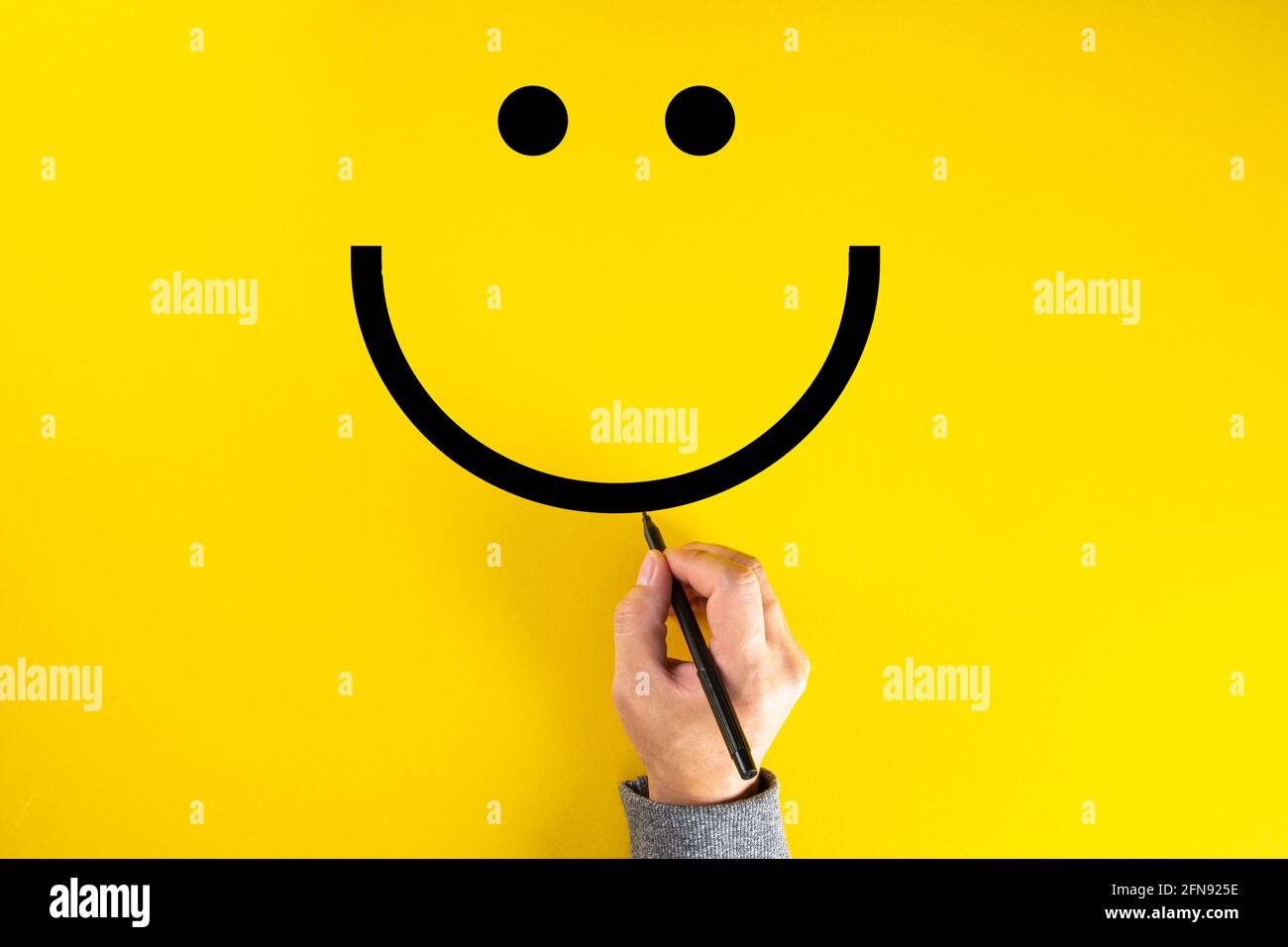 Male hand drawing a smiling happy face sketch on yellow background ...