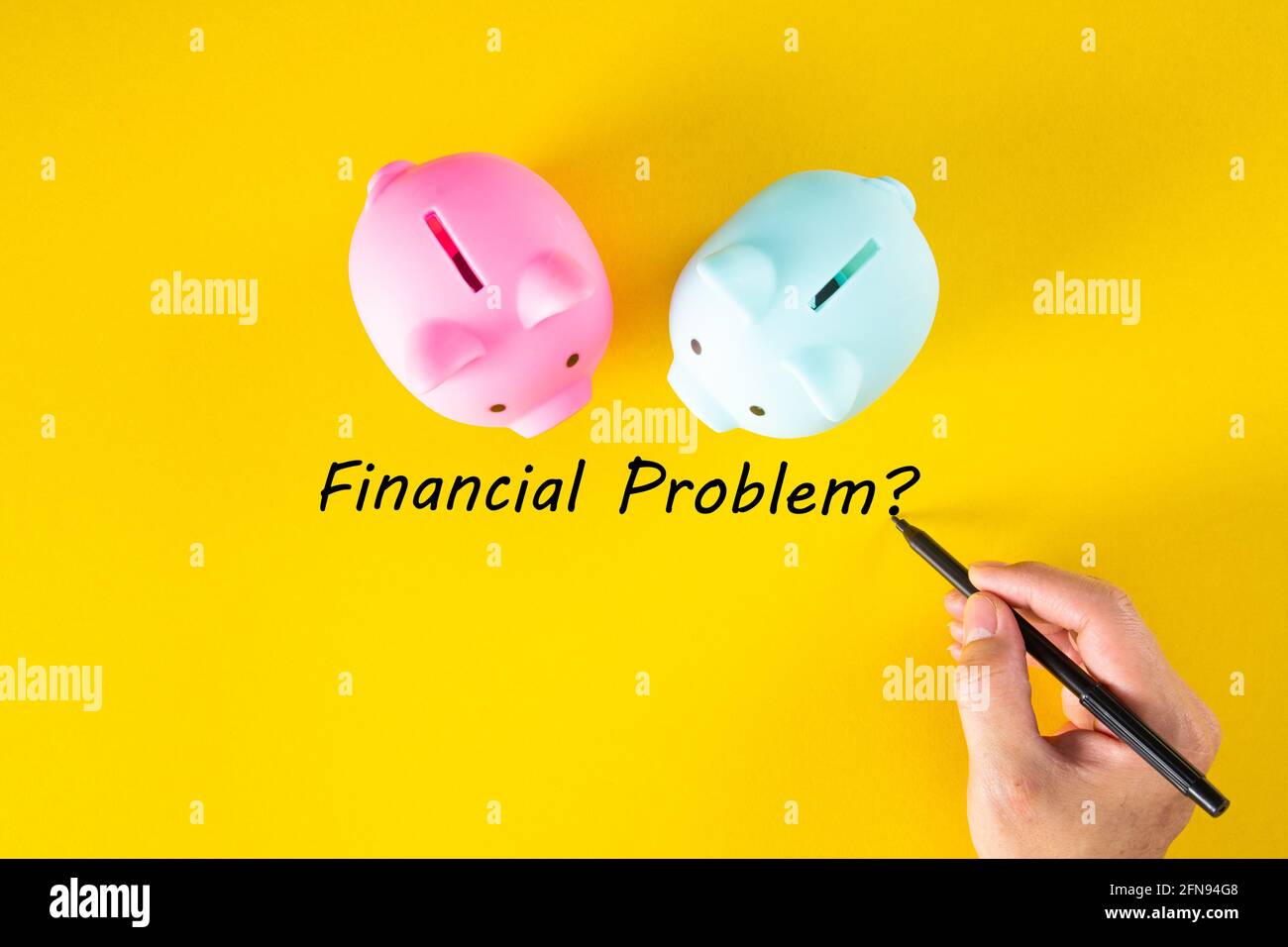 A hand writes the words FINANCIAL PROBLEM on the yellow background ...