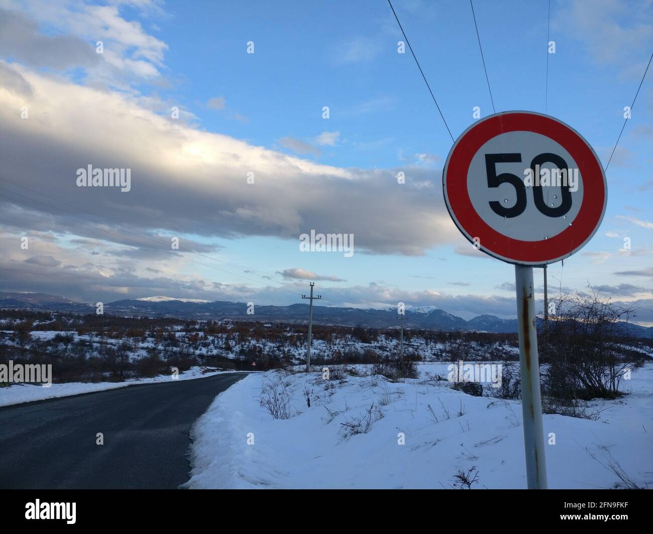 speed limit sign on a lonely mountain road in winter with a lot of snow ...