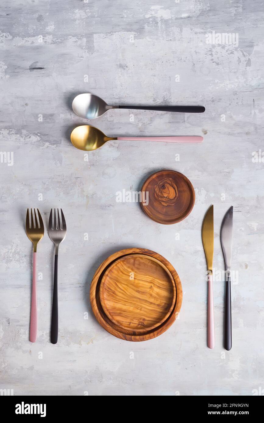 Flat lay of wooden plate and cutlery utensils on grey background. Empty ...