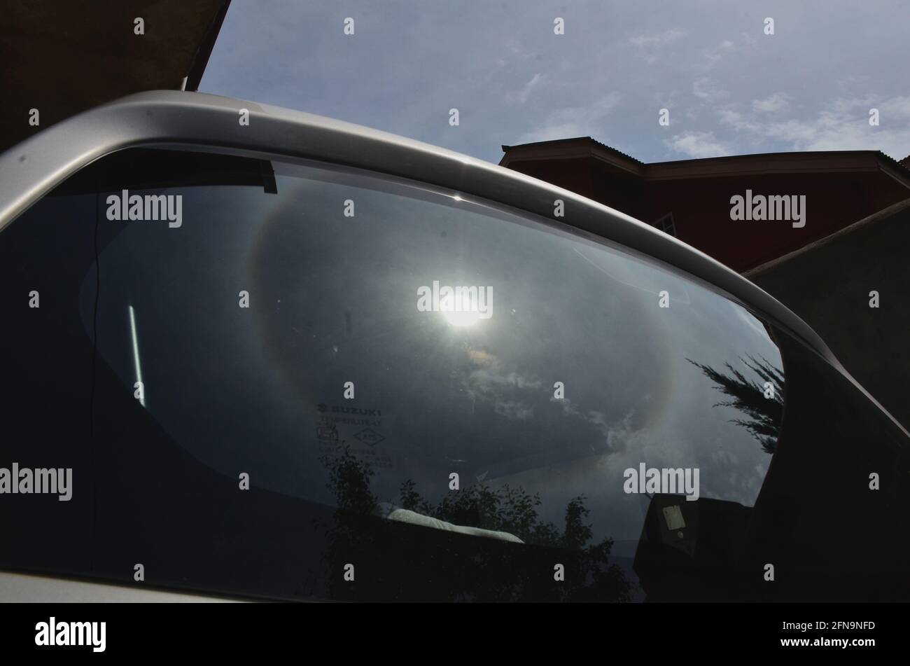 The halo phenomenon around the sun is reflected on a car window in ...