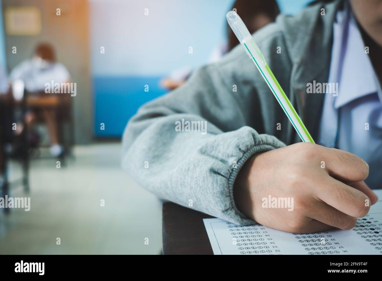 Students writing and reading exam answer sheets exercises in classroom ...