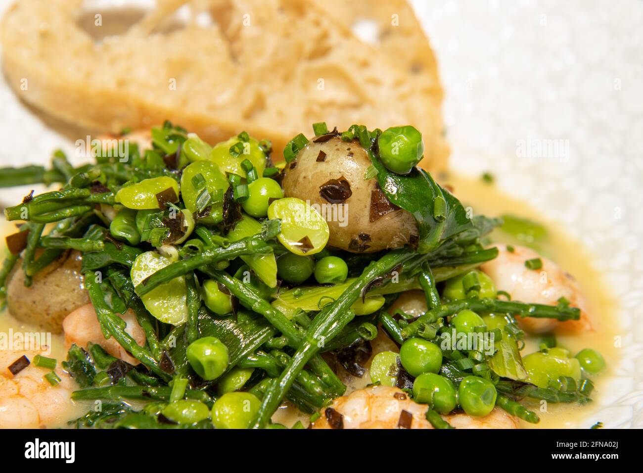 A delicious plate of potatoes fricassee with tiger prawns and green ...