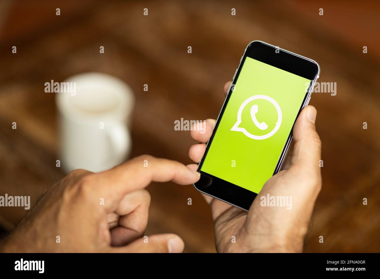 Man holding a smartphone in a cafe. Whatsapp logo on the display ...