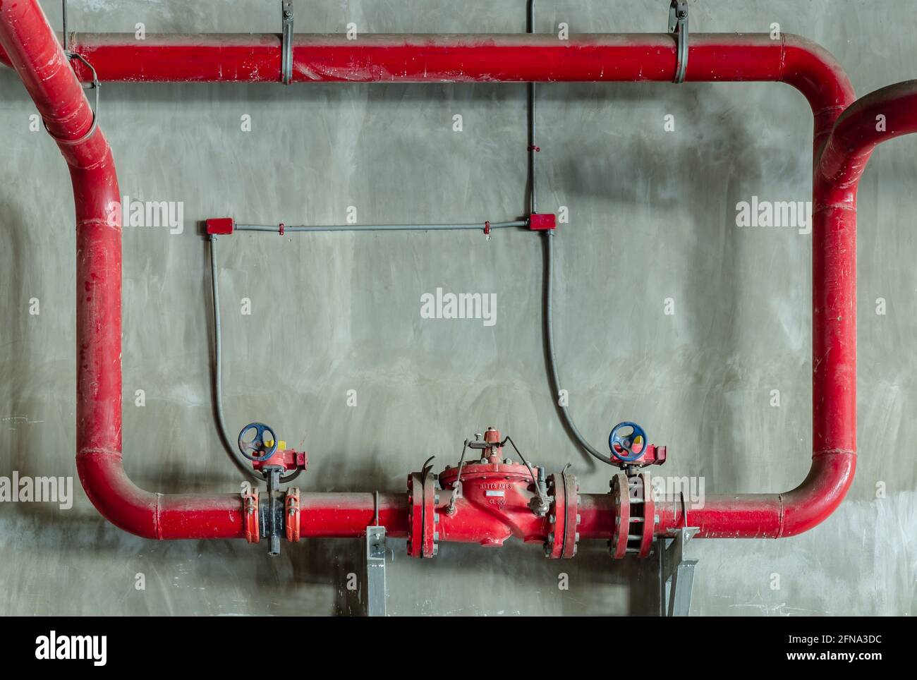 Red water or gas pipeline with gate pressure valve on concrete wall ...