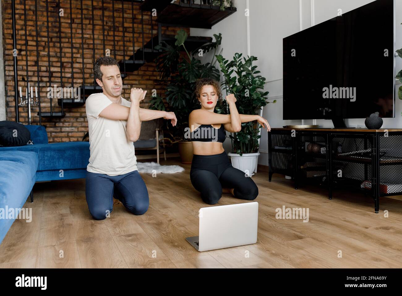 Young Caucasian sporty couple watching live or video tutorial practice ...