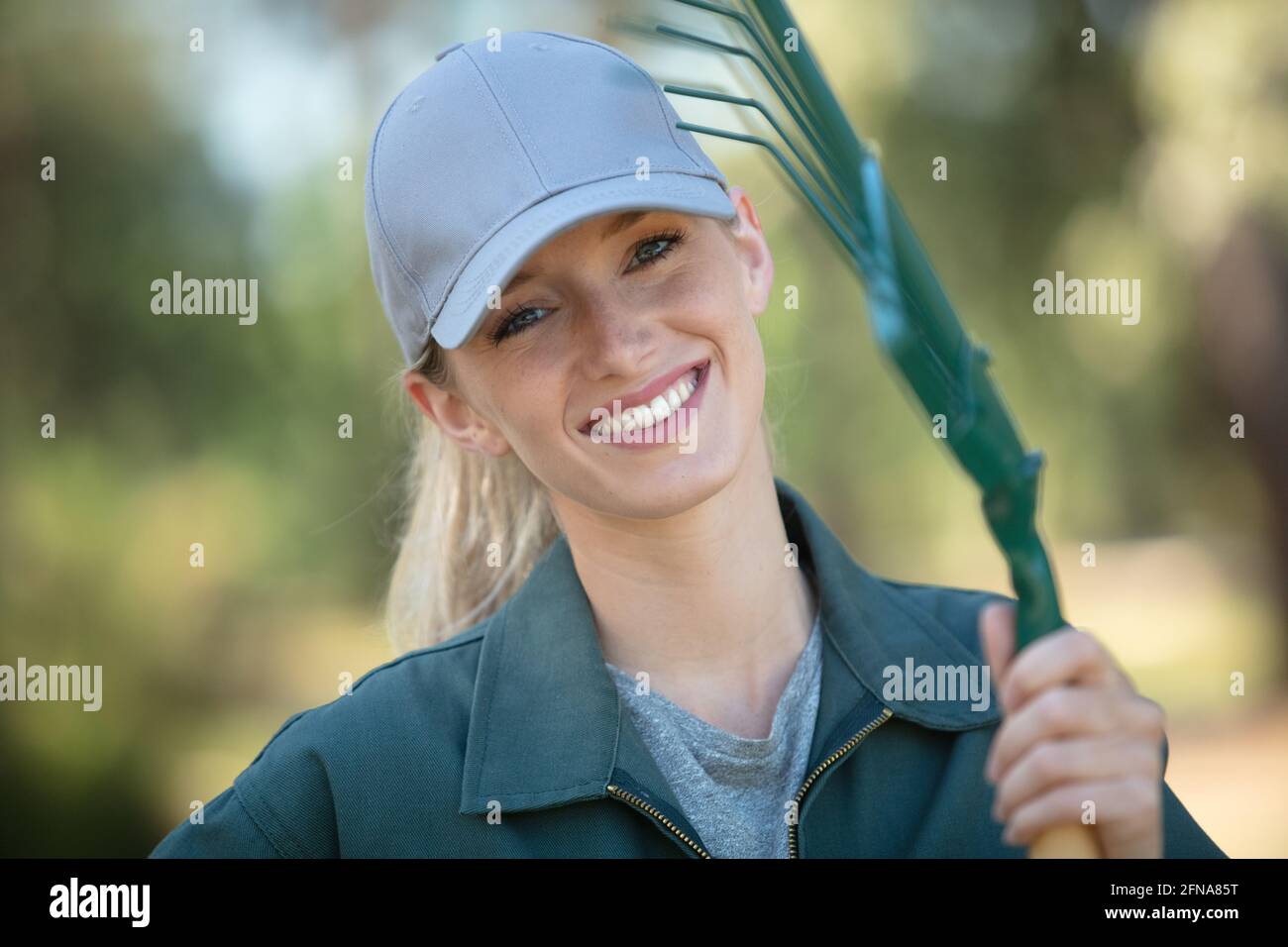pretty female gardener holding a rake Stock Photo - Alamy
