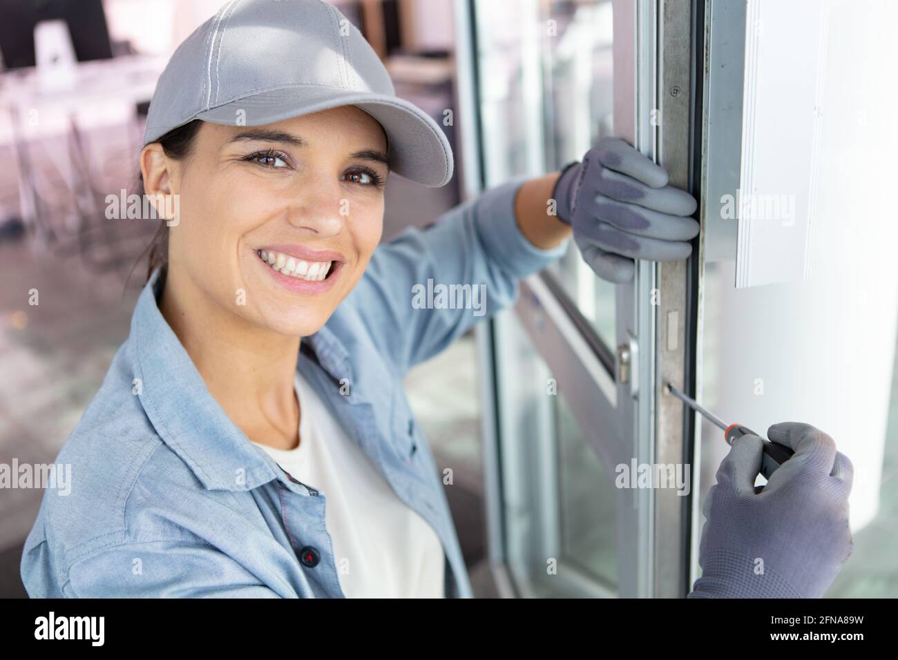 happy female builder using a screwdriver on a door Stock Photo - Alamy