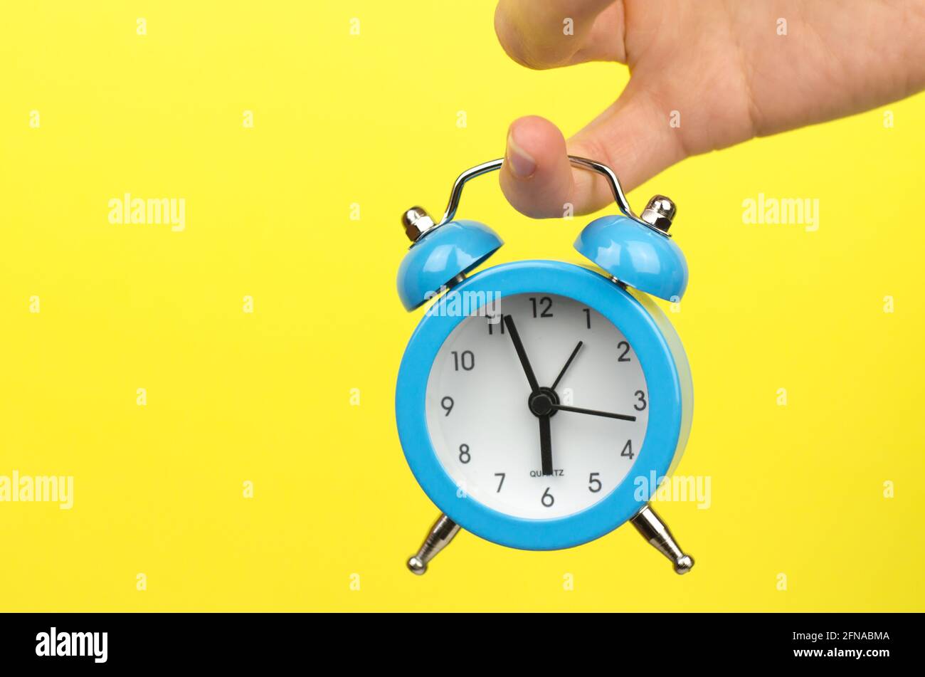 Small blue alarm clock hanging on the finger of a female hand Stock ...