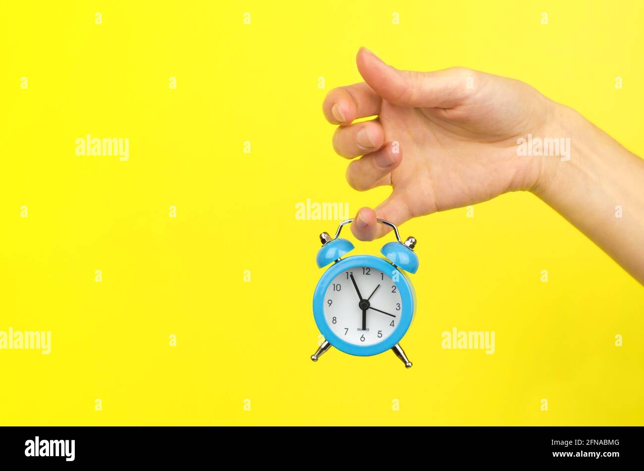 Small blue alarm clock hanging on the finger of a female hand Stock ...