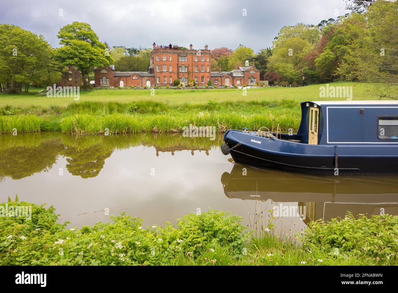 Canal narrowboat on the Macclesfield canal as it passes Ramsdell Hall ...