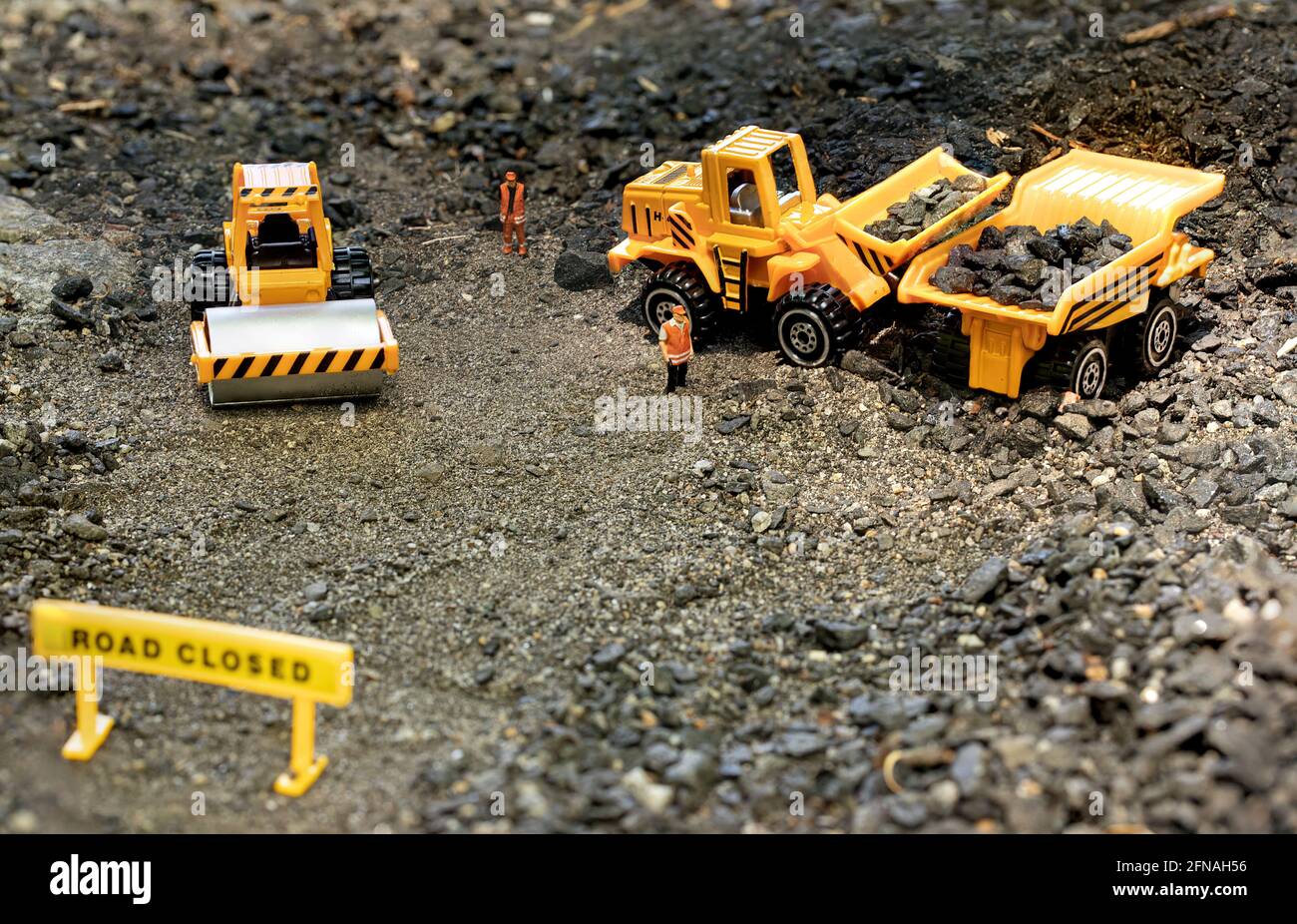 Toy workers in road construction diorama load rocks into haul truck ...