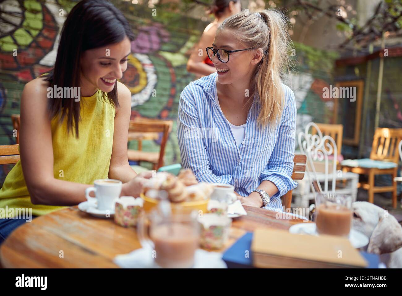 Female friends chatting in a bar's garden on a beautiful day. Leisure ...