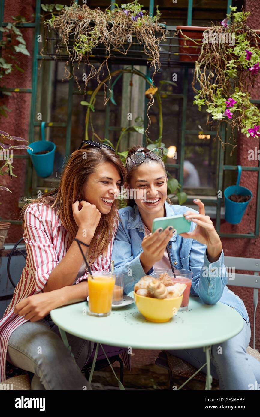Two beautiful girls are enjoying a smartphone content while sitting in a pleasant atmosphere in ...