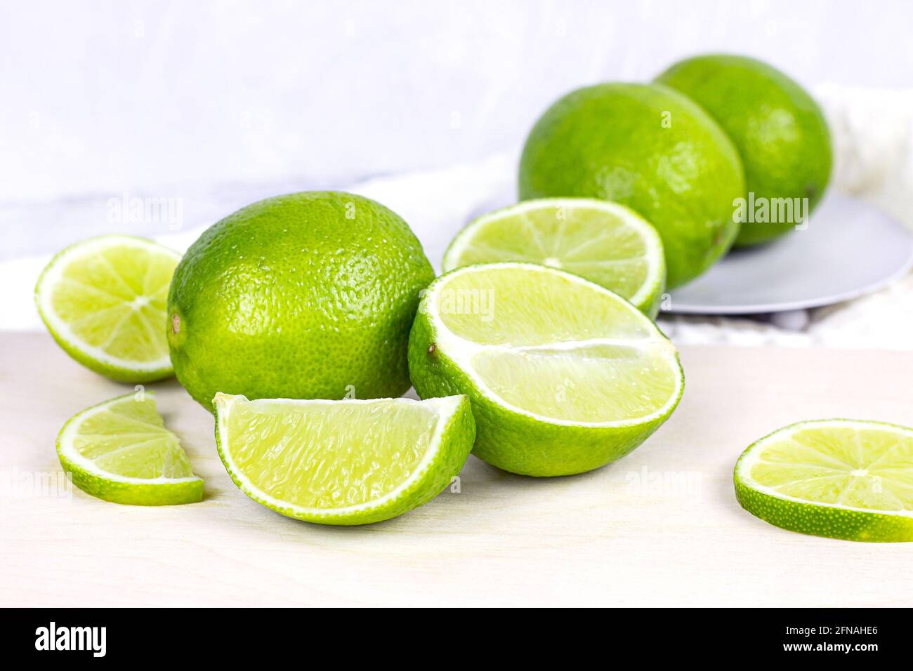 Fresh green juicy limes and lime slices in the kitchen on light ...